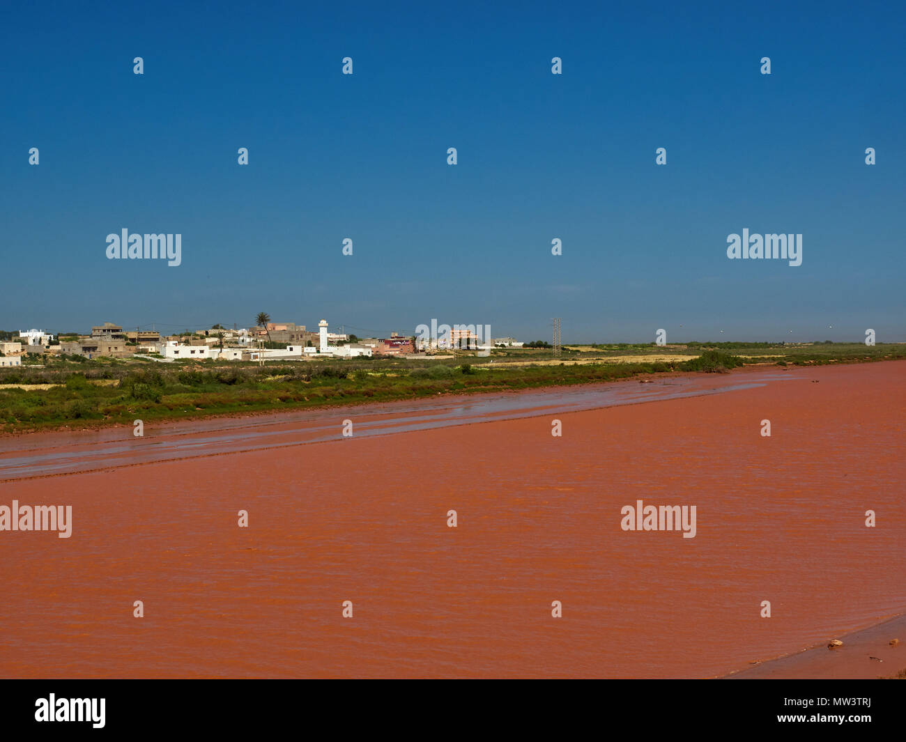 Traditional Berber village on the clay river bank with red water, in ...
