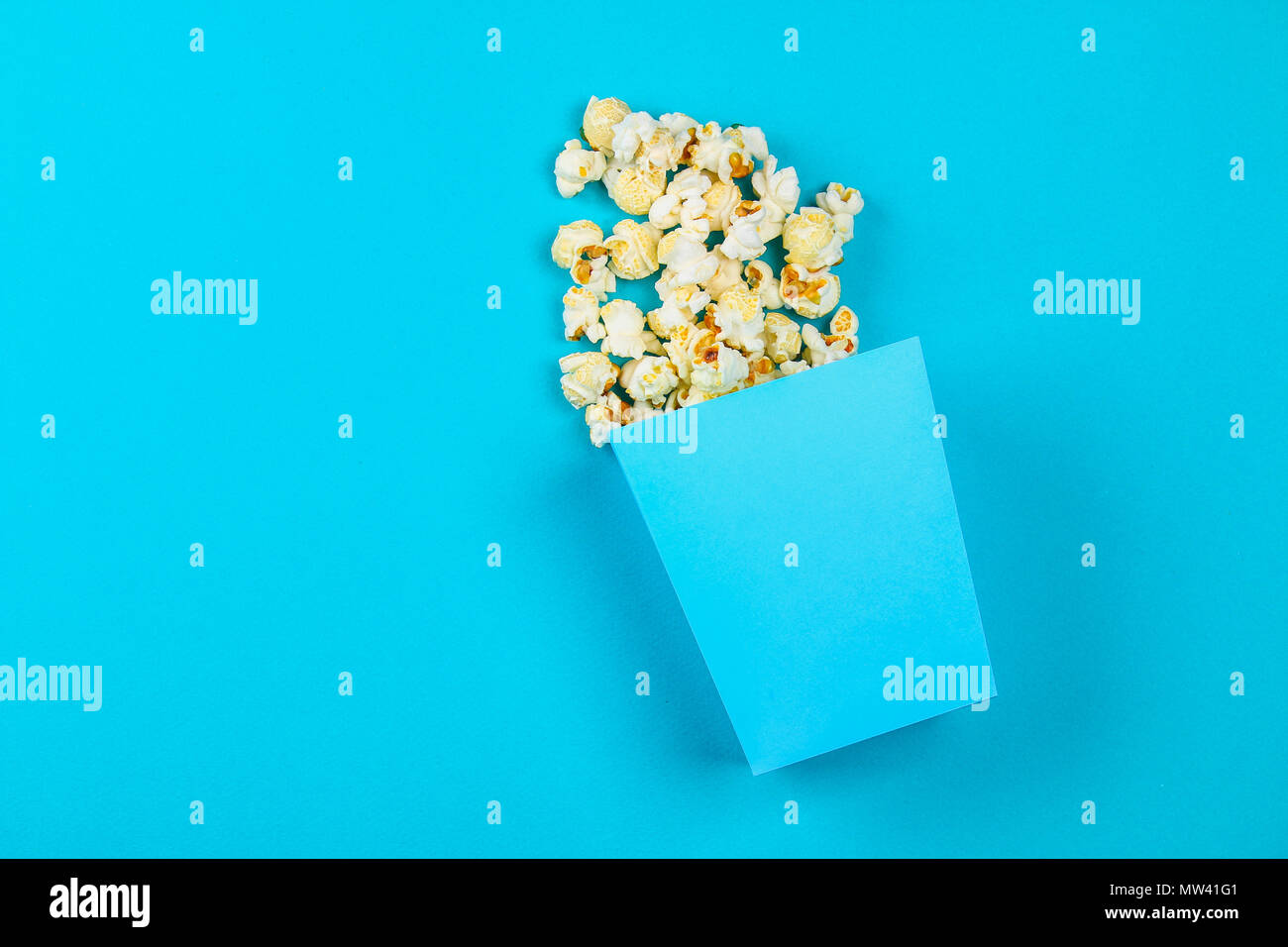 Box of popcorn spilled on blue background Stock Photo - Alamy