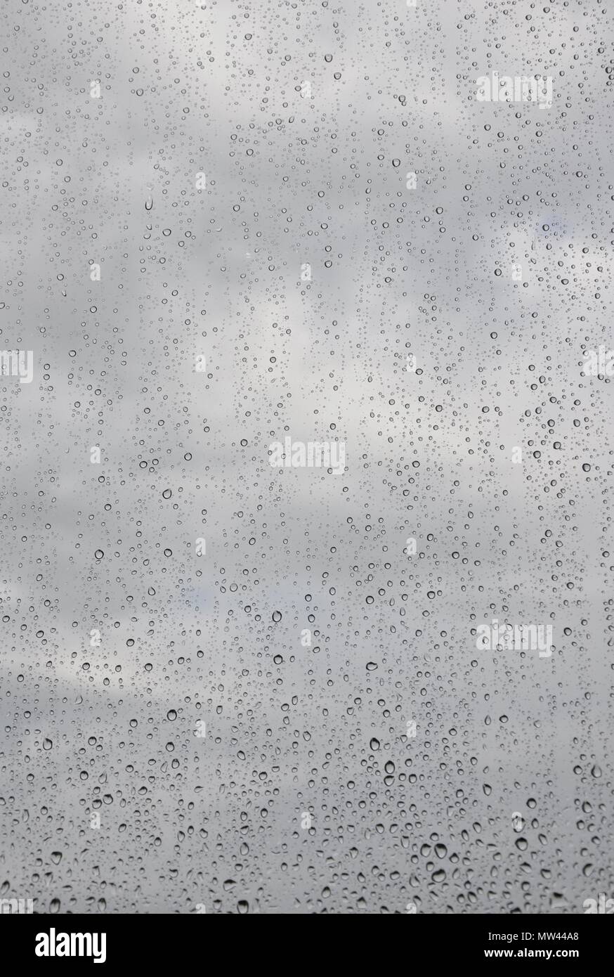 Raindrops on transparent window with cloudy sky background, closeup ...