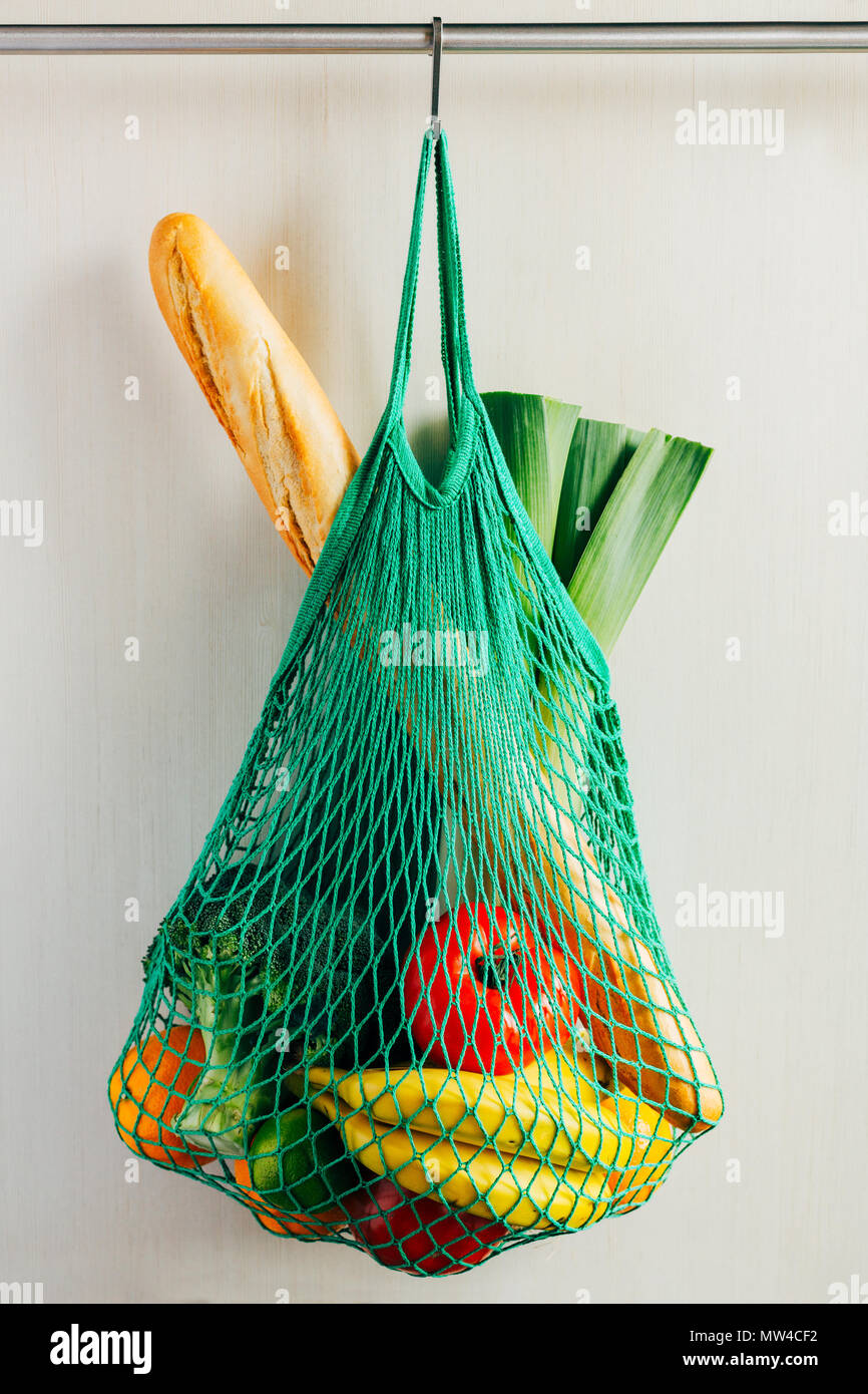 Green string shopping bag with vegetables, fruits and bread hanging on ...