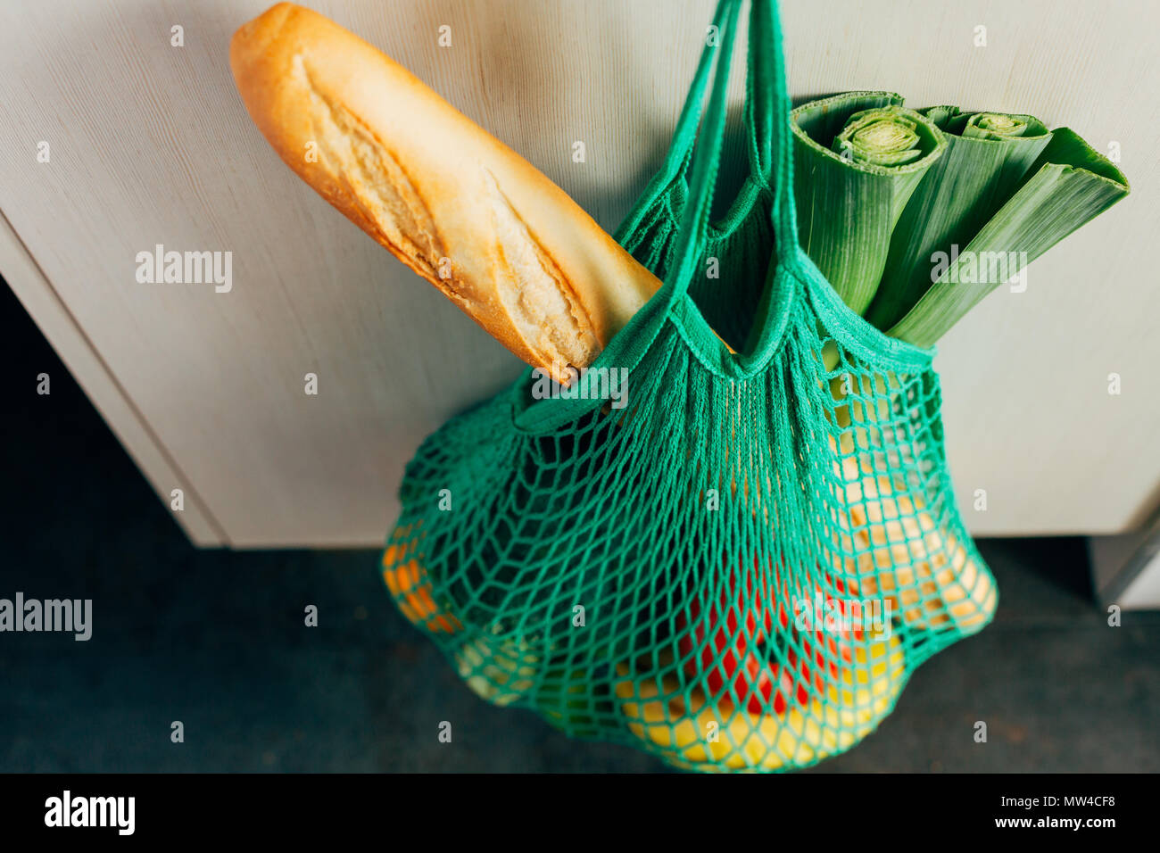 Green string shopping bag with vegetables, fruits and bread hanging on ...