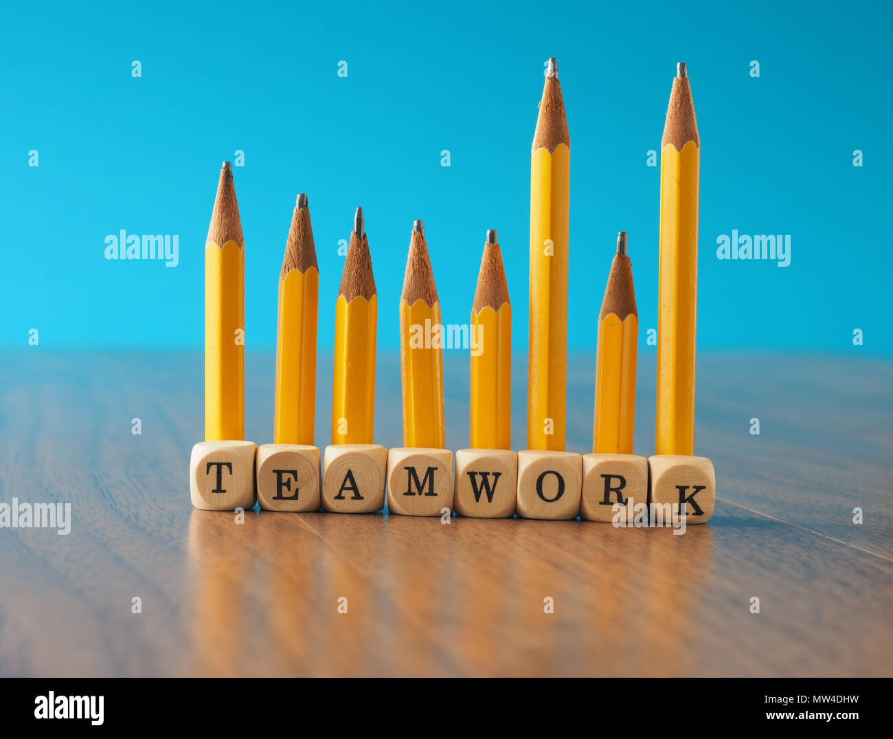 Teamwork concept with a row of yellow pencils and wooden dices with the ...