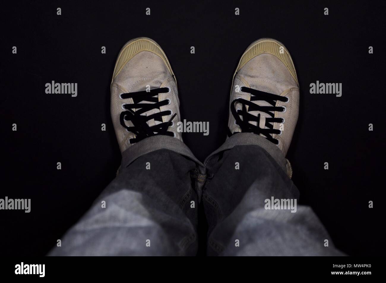 Man wearing sneakers and blue jeans on black background Stock Photo - Alamy