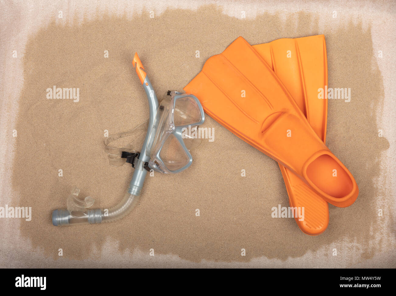 Diving equipment—orange diving mask ,snorkel and flippers on sandy ...