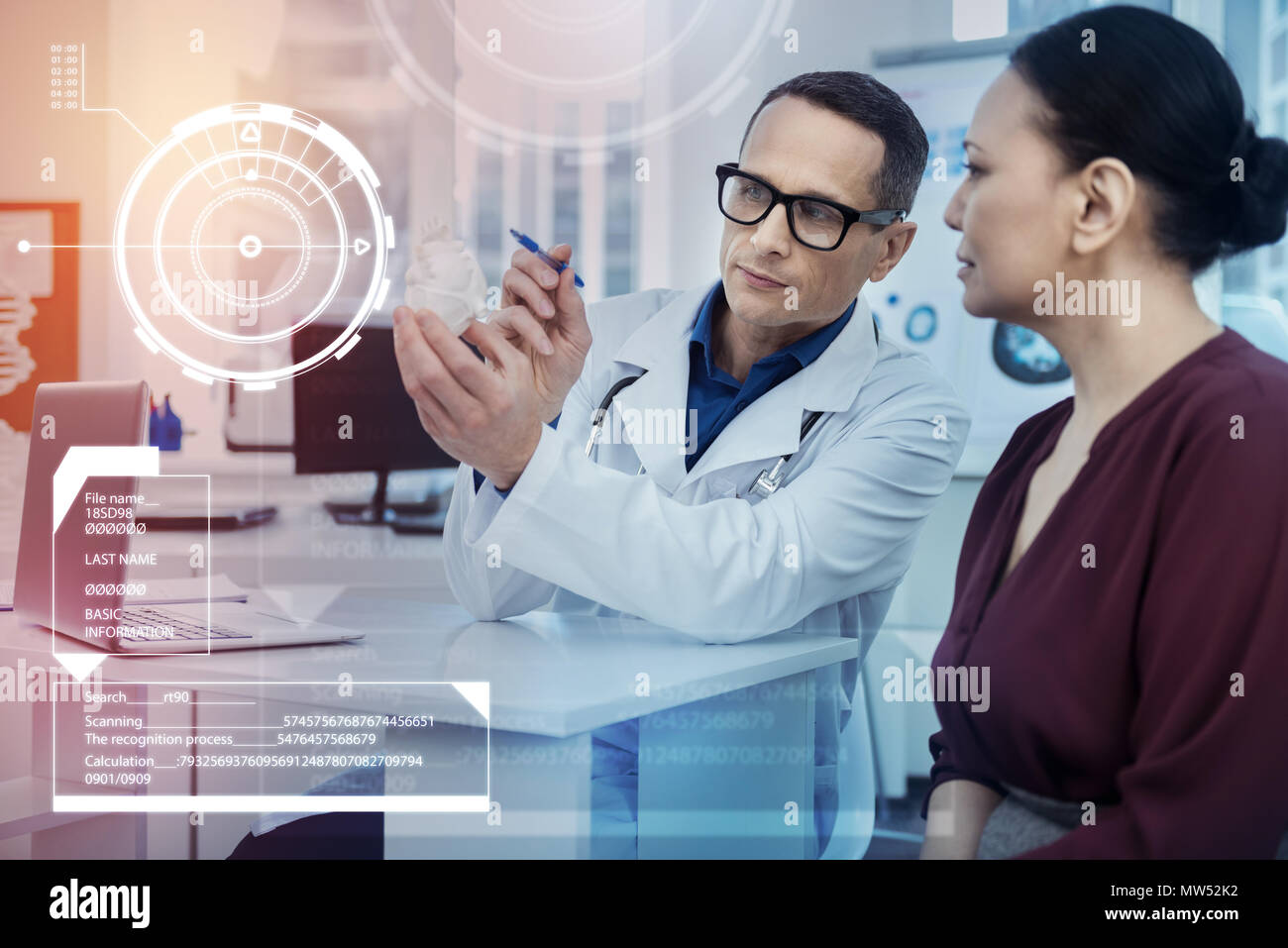 Curious patient sitting near her doctor and looking at the heart ...