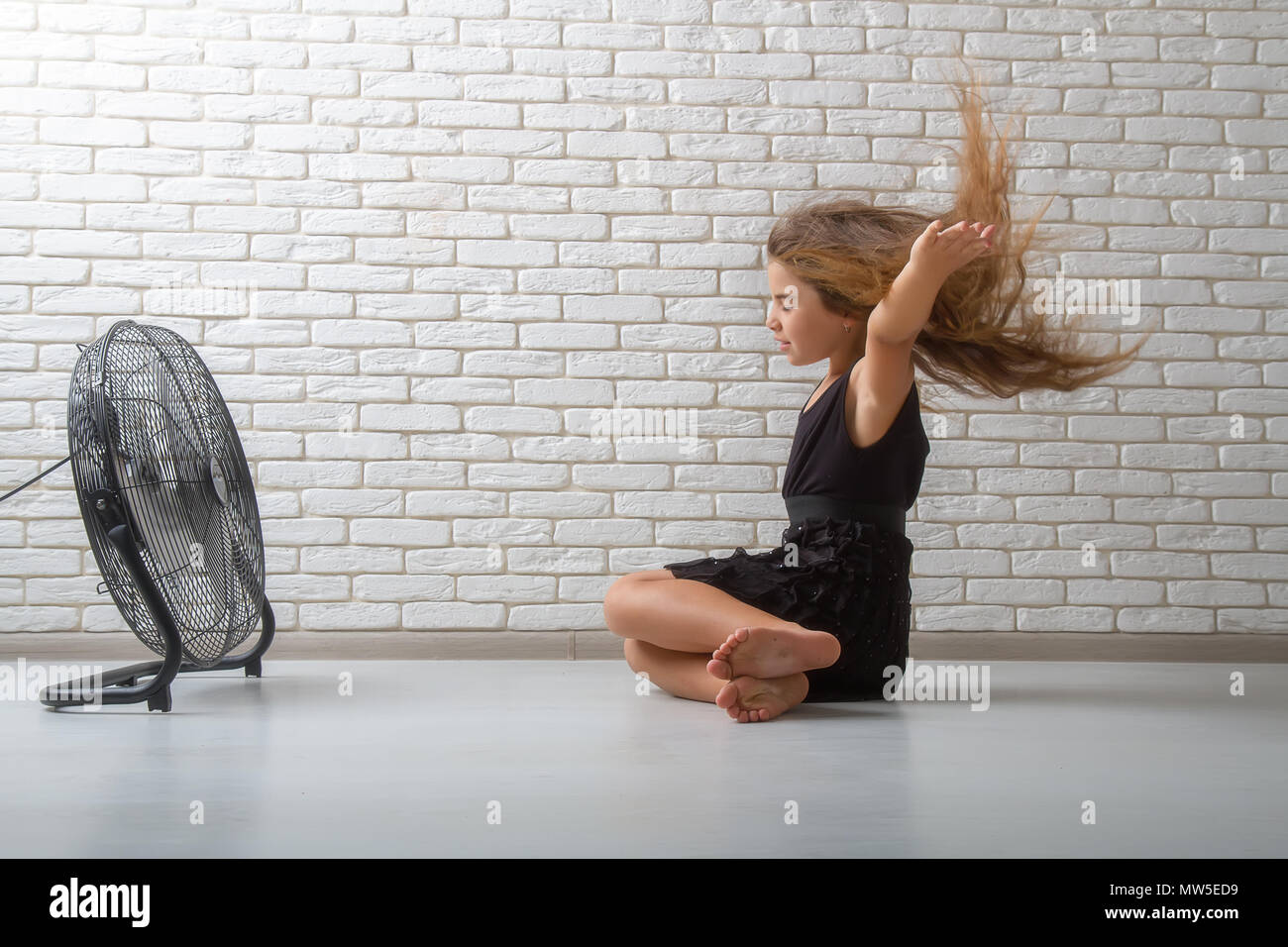 the girl is sitting in front of the fan Stock Photo - Alamy