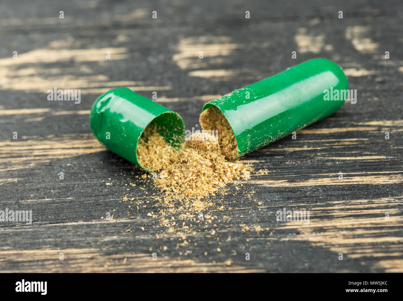Open green herbal capsule on table close up Stock Photo - Alamy