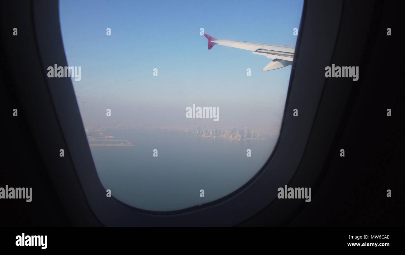 View through an airplane window on the city Qatar. Airplane window view ...