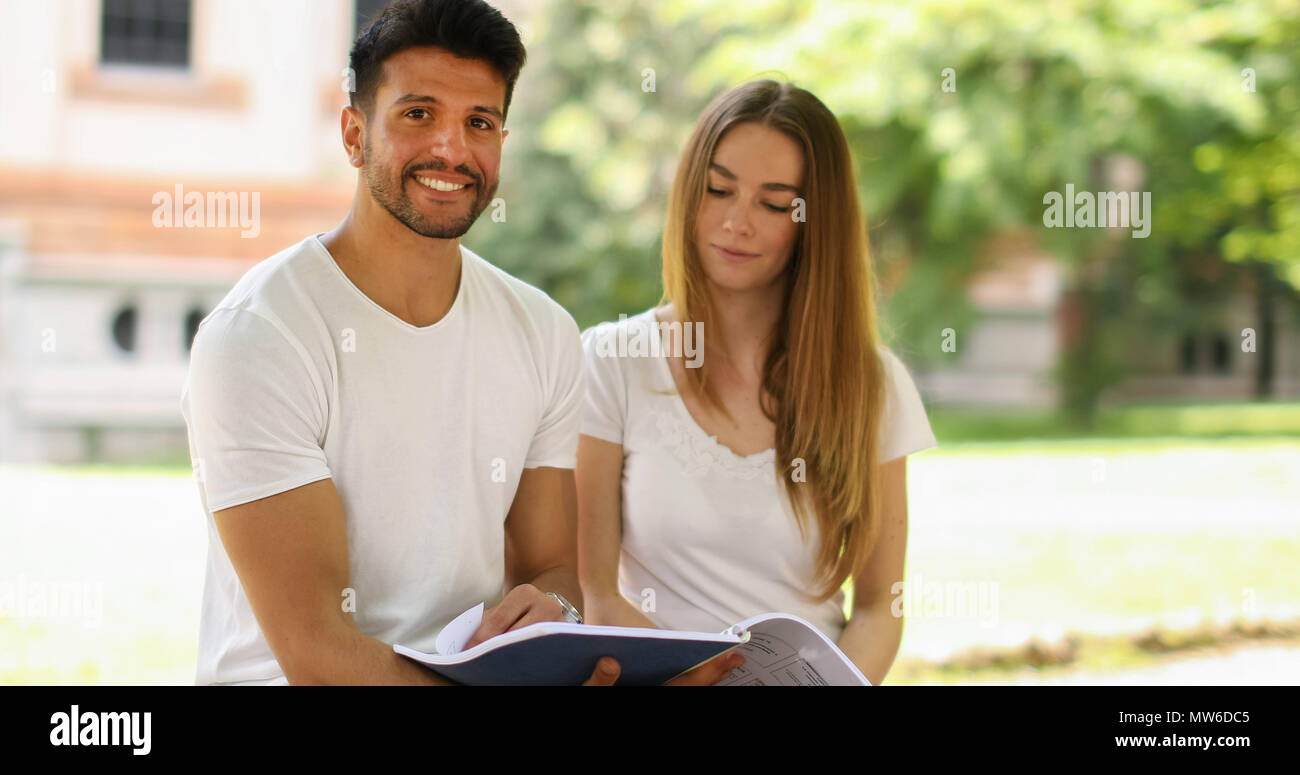 Two students studying together sitting on a bench outdoor Stock Photo ...