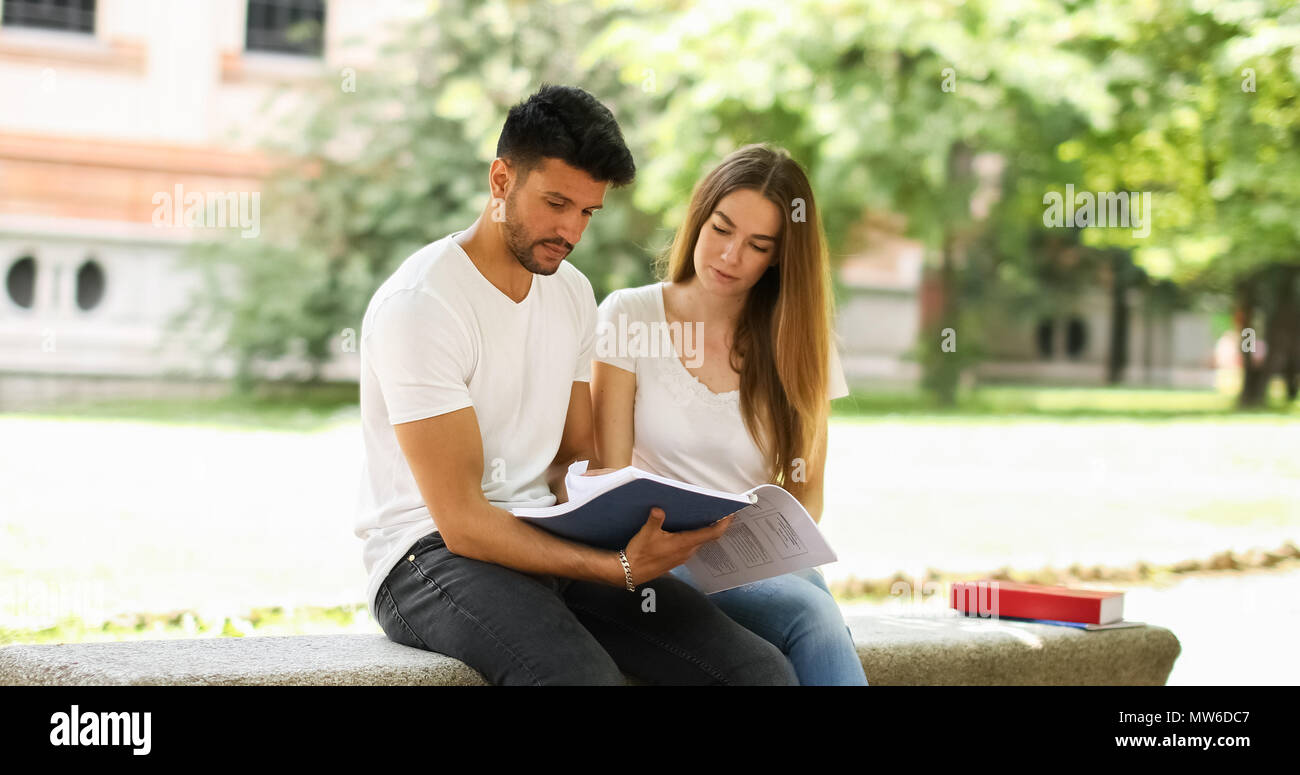 Two students studying together sitting on a bench outdoor Stock Photo ...