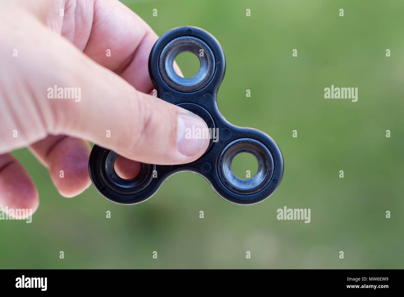 Hand holding black fidget spinner, stress relieving toy isolated on ...