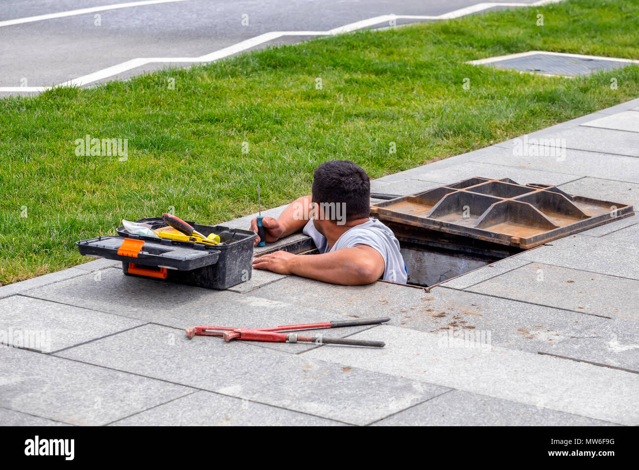 Working in manhole, worker making repairs on water supply at city ...