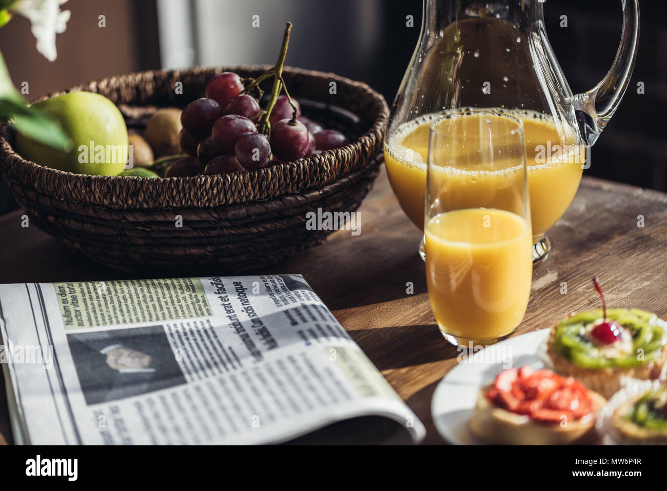 Still life of newspaper, breakfast with cakes, juice and fruits on ...
