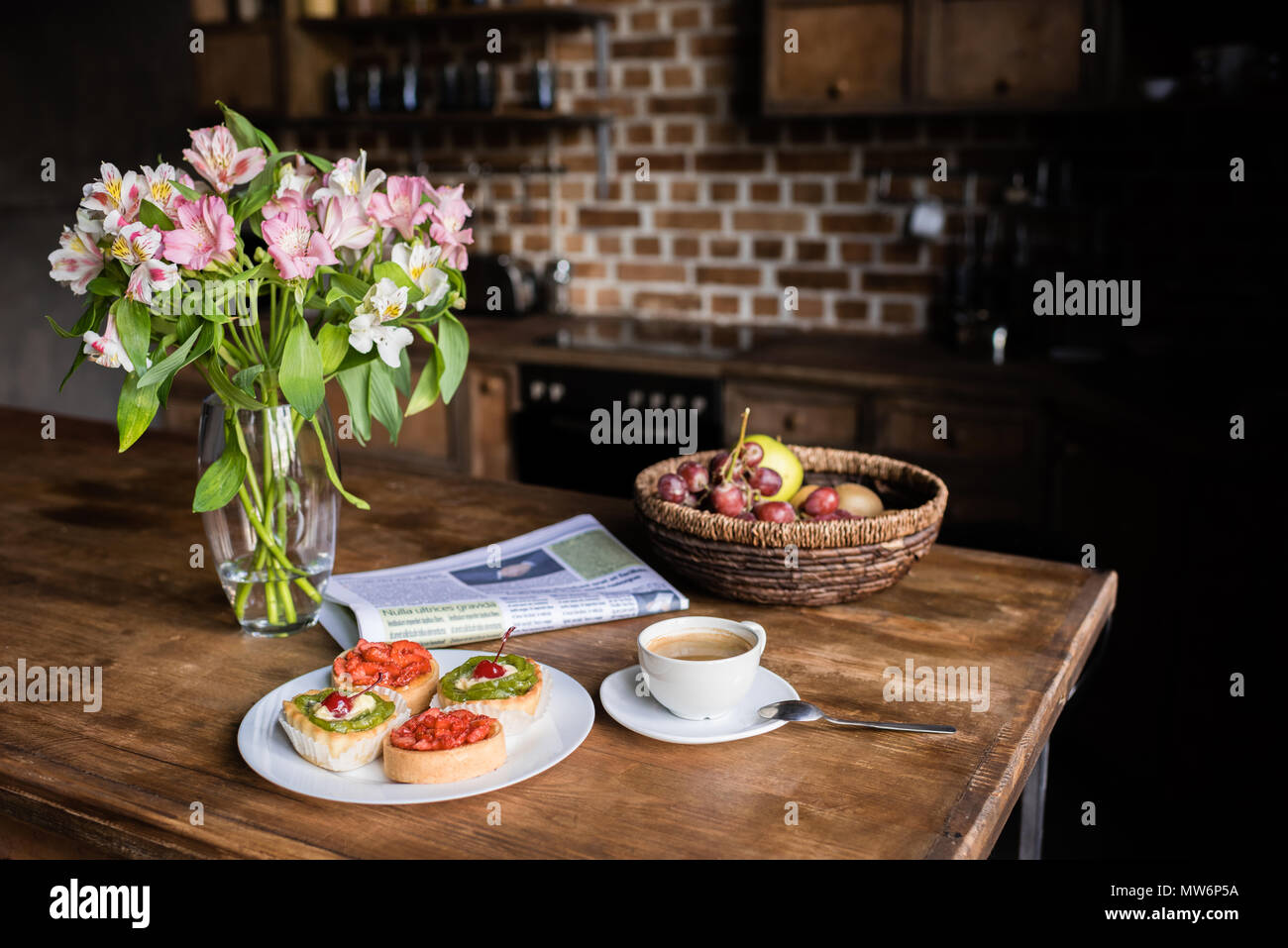 Still life of flowers, newspaper, breakfast with cakes, coffee and ...