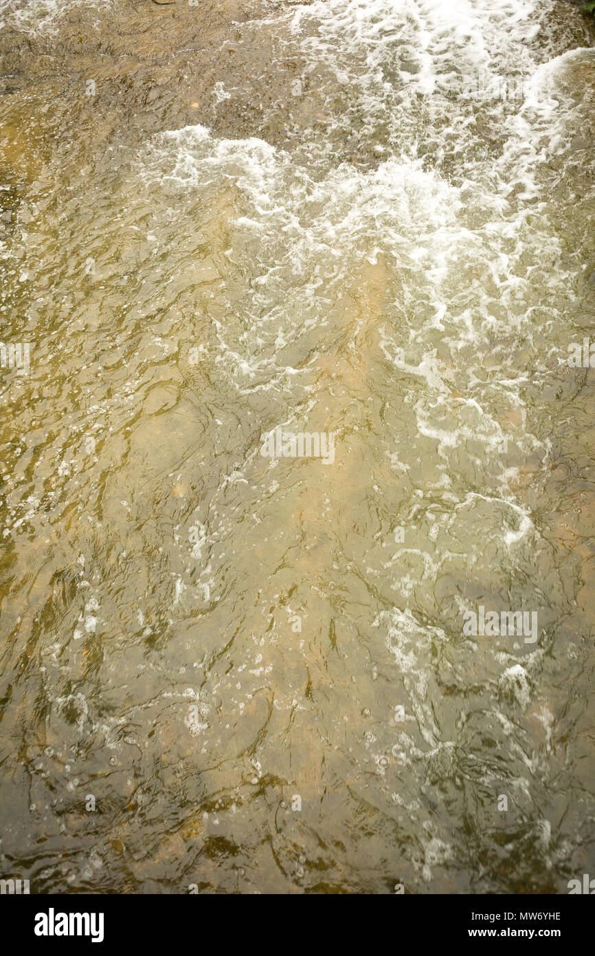Fast flowing water running and splashing over wet rocks Stock Photo - Alamy