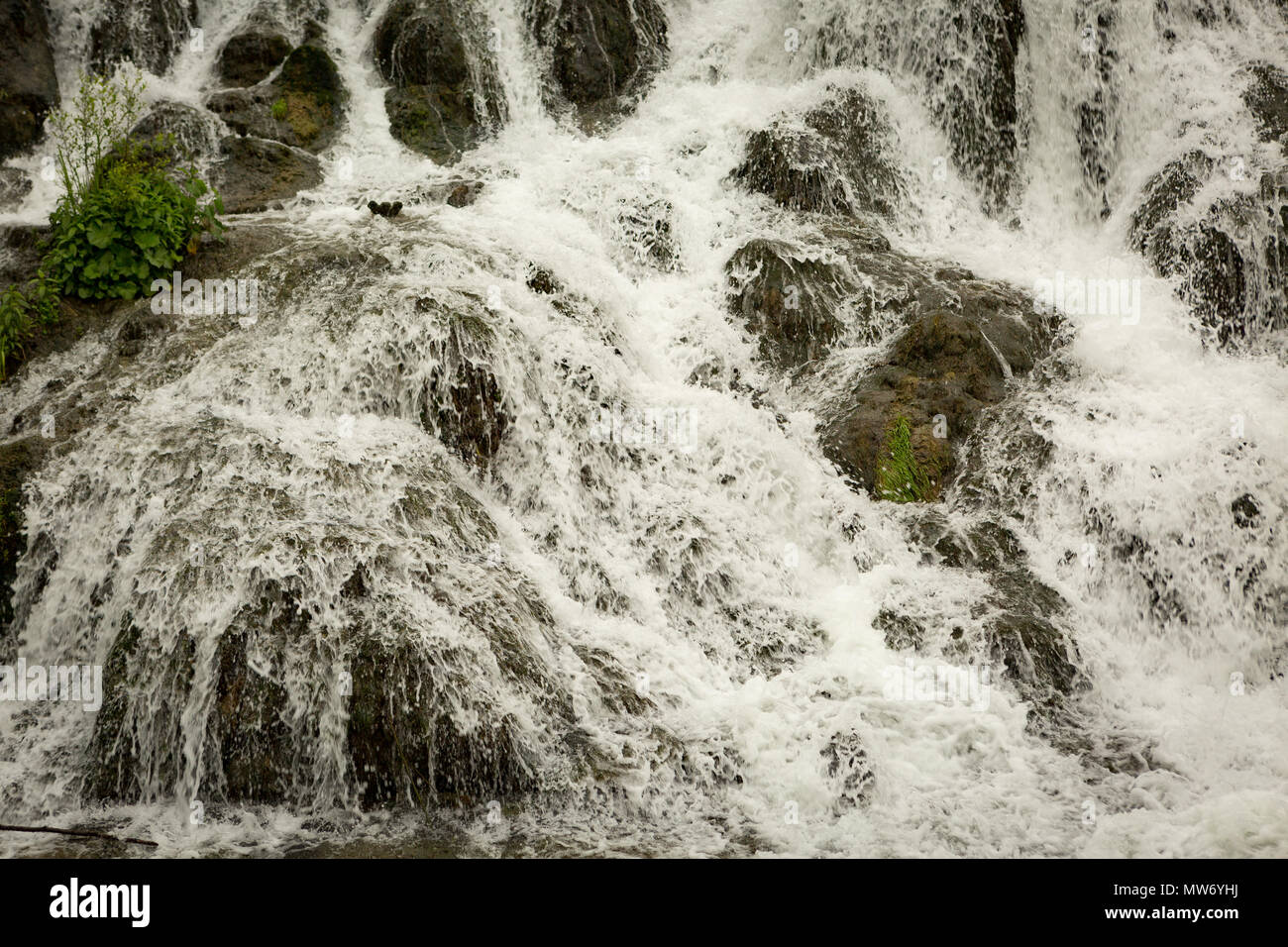 Fast flowing water running and splashing over wet rocks Stock Photo - Alamy