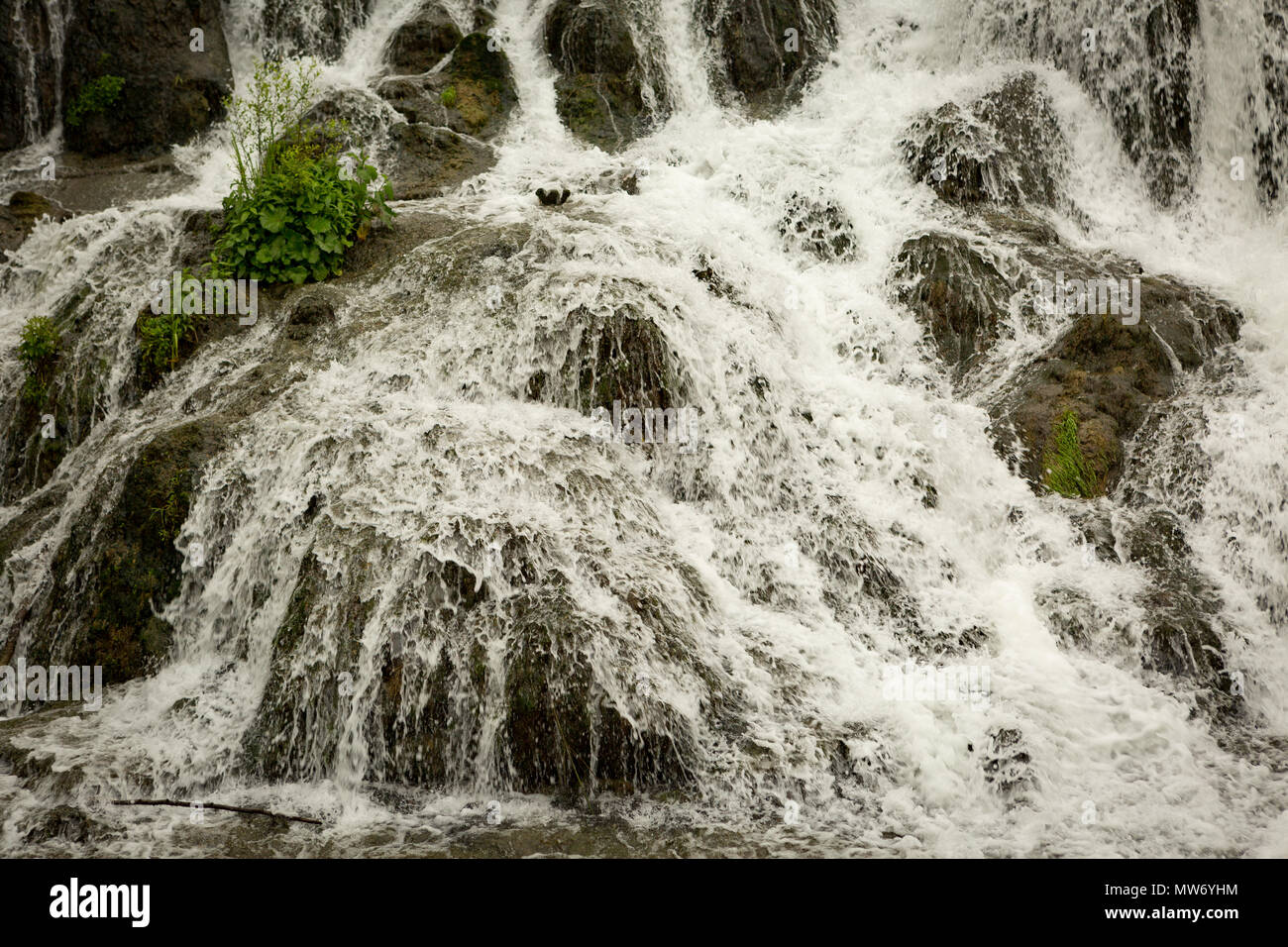 Fast flowing water running and splashing over wet rocks Stock Photo - Alamy