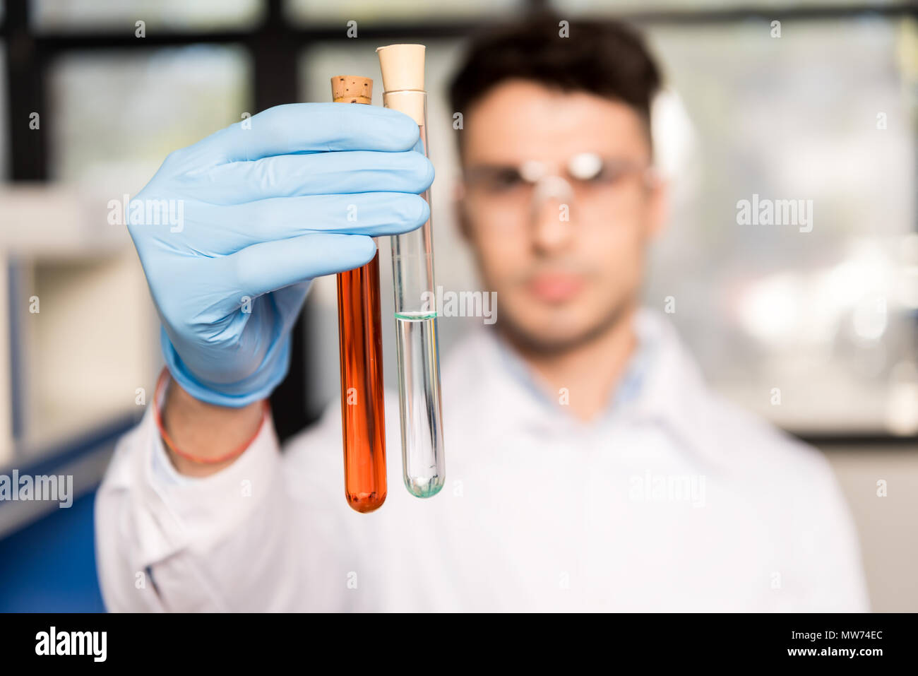 Young scientist showing test tubes with different colored liquids Stock ...
