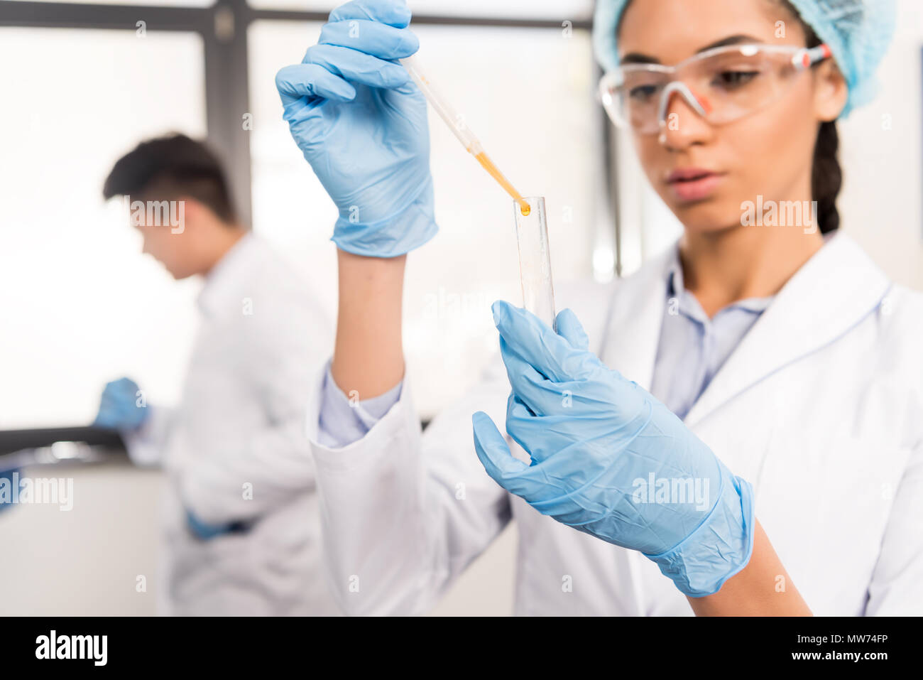 Young scientist dropping liquid into test tube with pipette Stock Photo ...