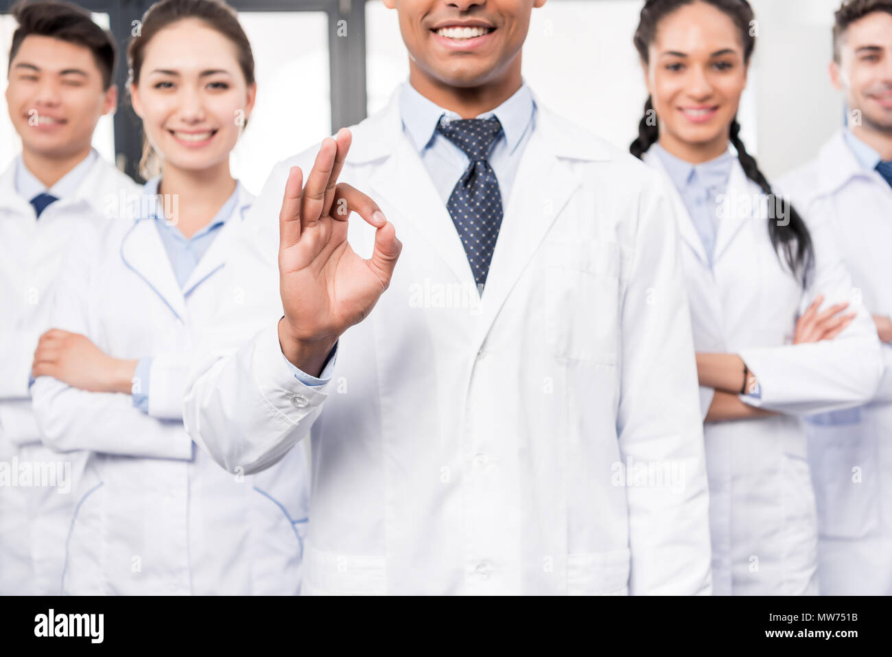 Team of smiling professional doctors standing together, while their ...