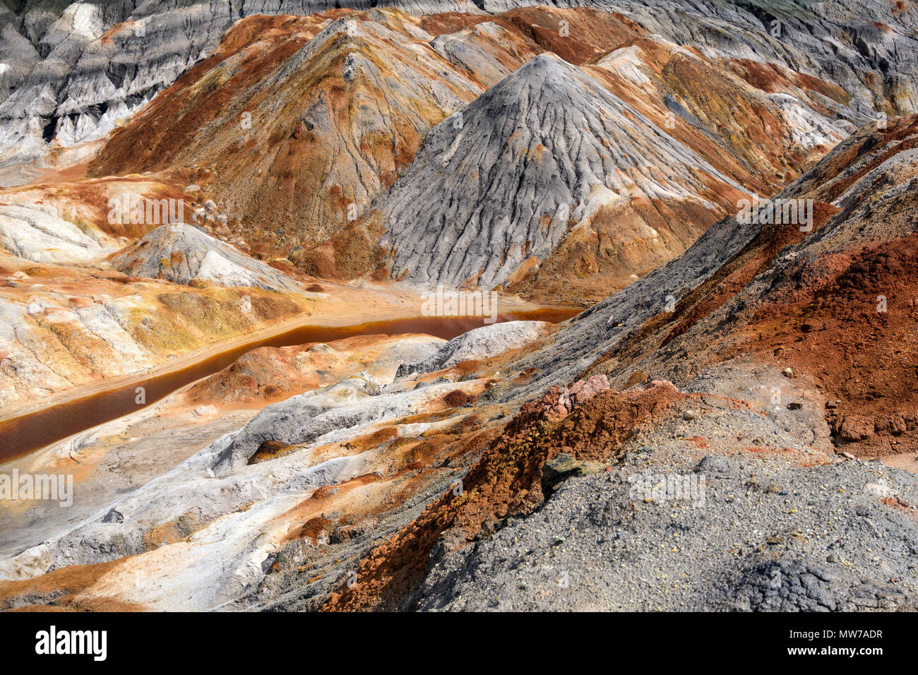 Canyon in the desert with multi-colored rugged slopes and a river with ...