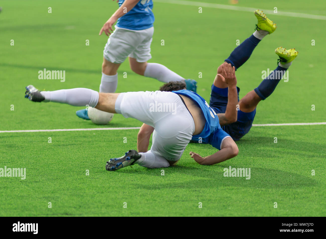 Football players tumbling on the football field. Falling players in the ...