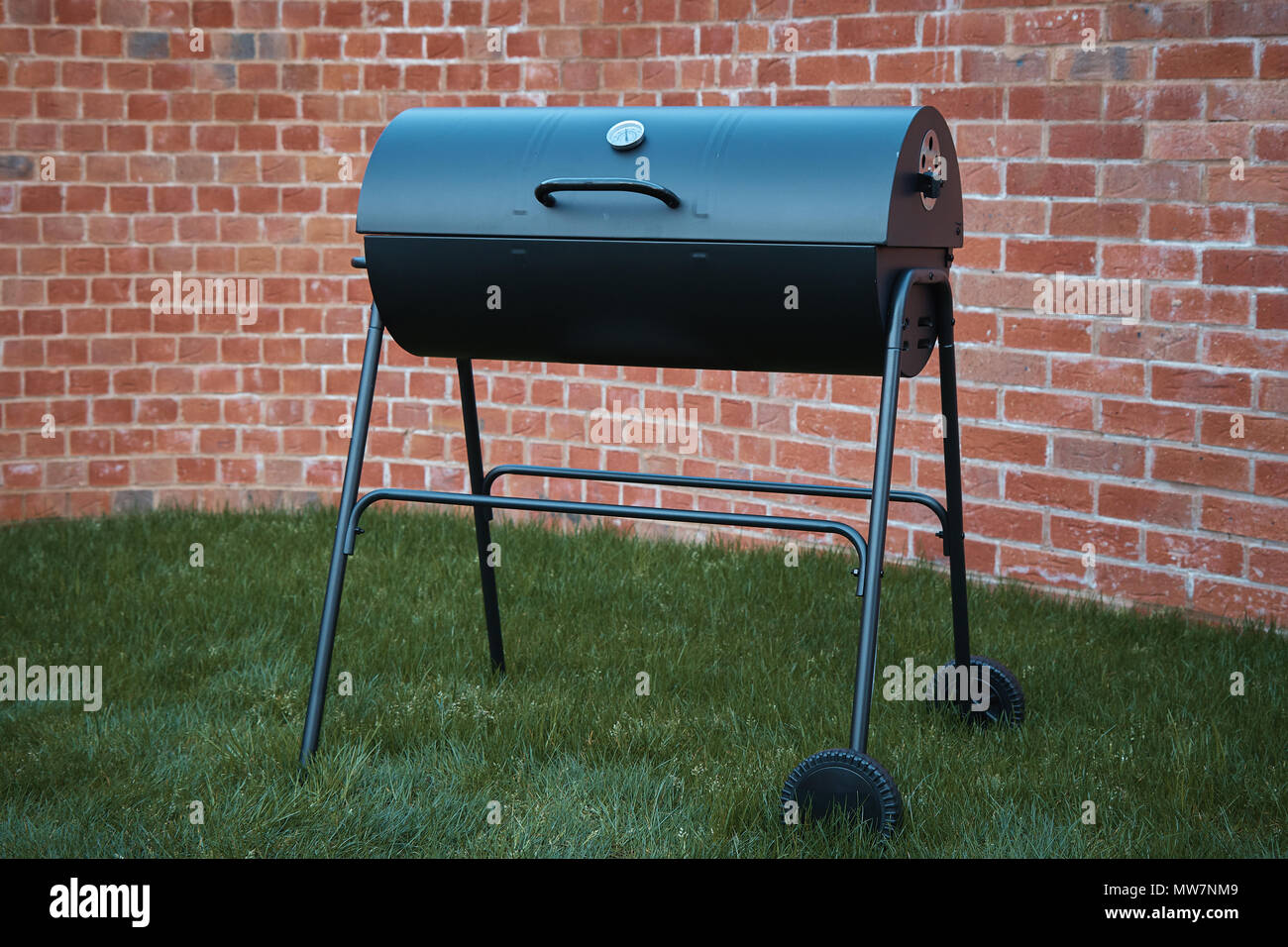 Black big barrel grill in the garden Stock Photo - Alamy