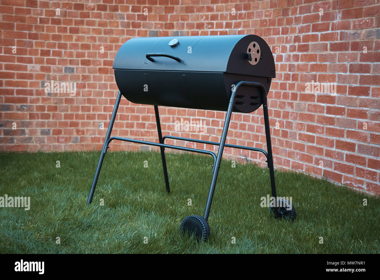 Black big barrel grill in the garden Stock Photo - Alamy