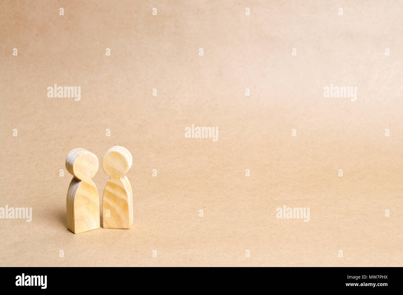 Two people stand together and talk. Two wooden figures of people ...