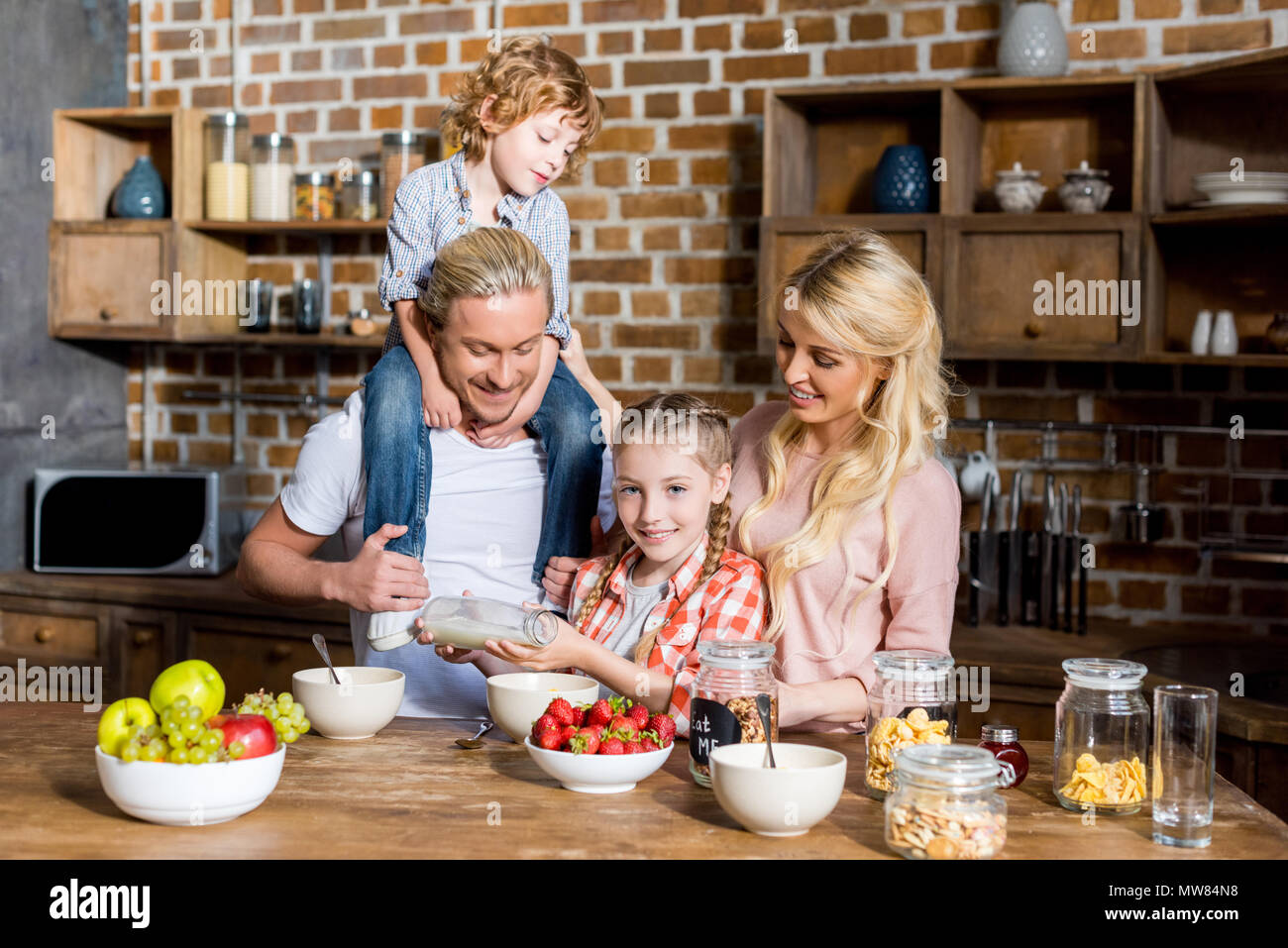 happy family with two children preparing and eating breakfast together ...