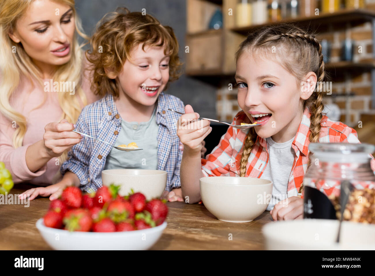 happy mother with cute little kids having breakfast at home Stock Photo - Alamy