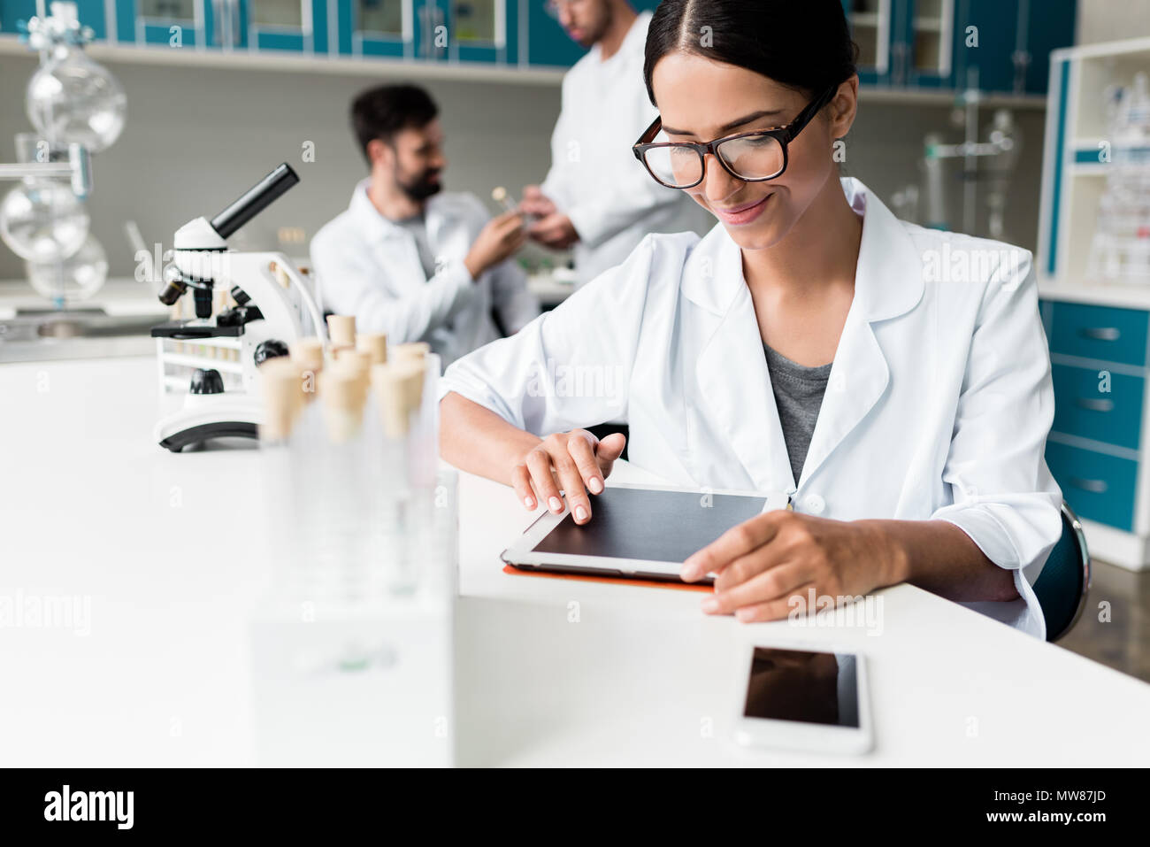 Smiling young female scientist using digital tablet with blank screen ...