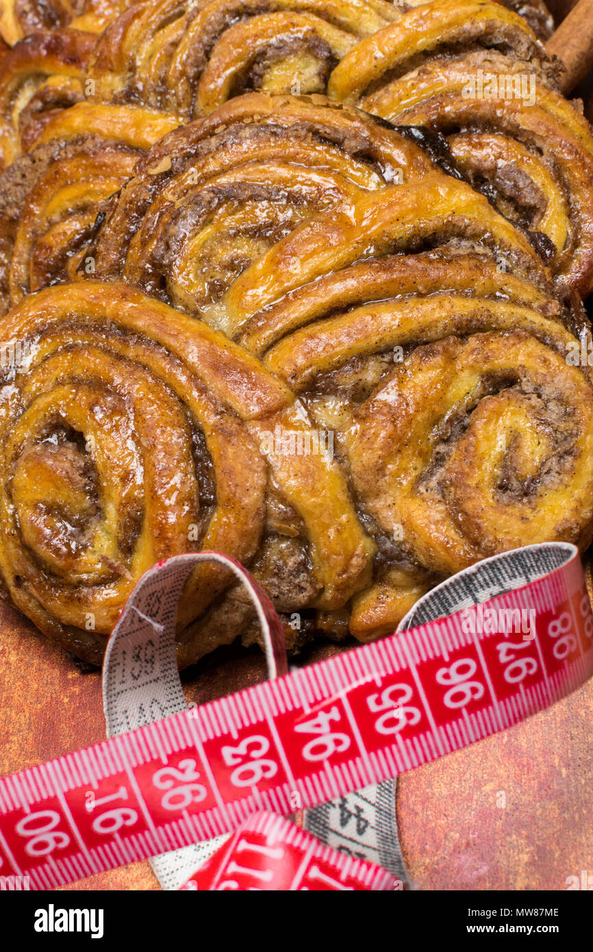 homemade sweet cinnamon rolls on red plate with sticks of cinnamons and ...