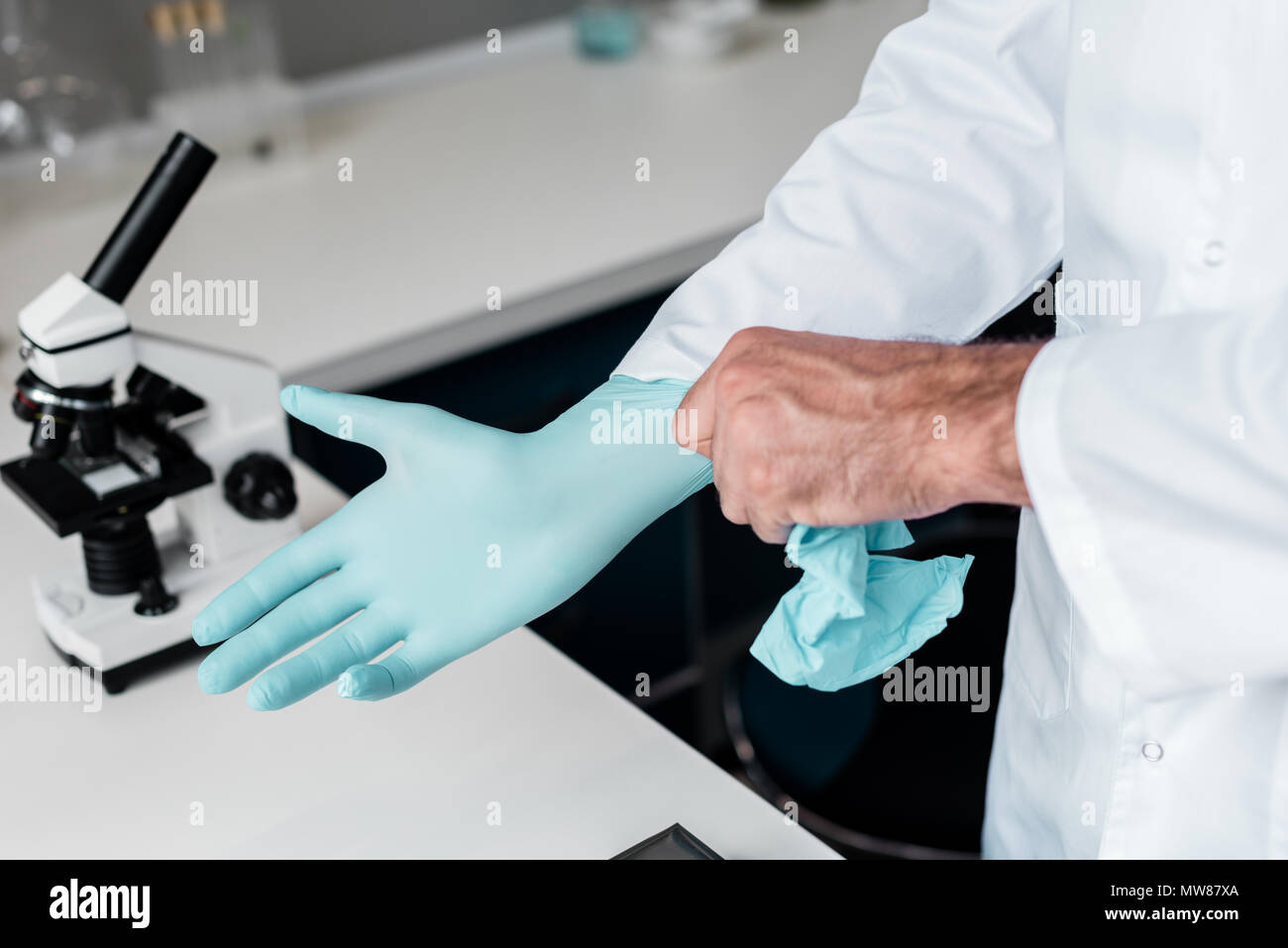 Cropped shot of professional scientist in white coat wearing protective ...