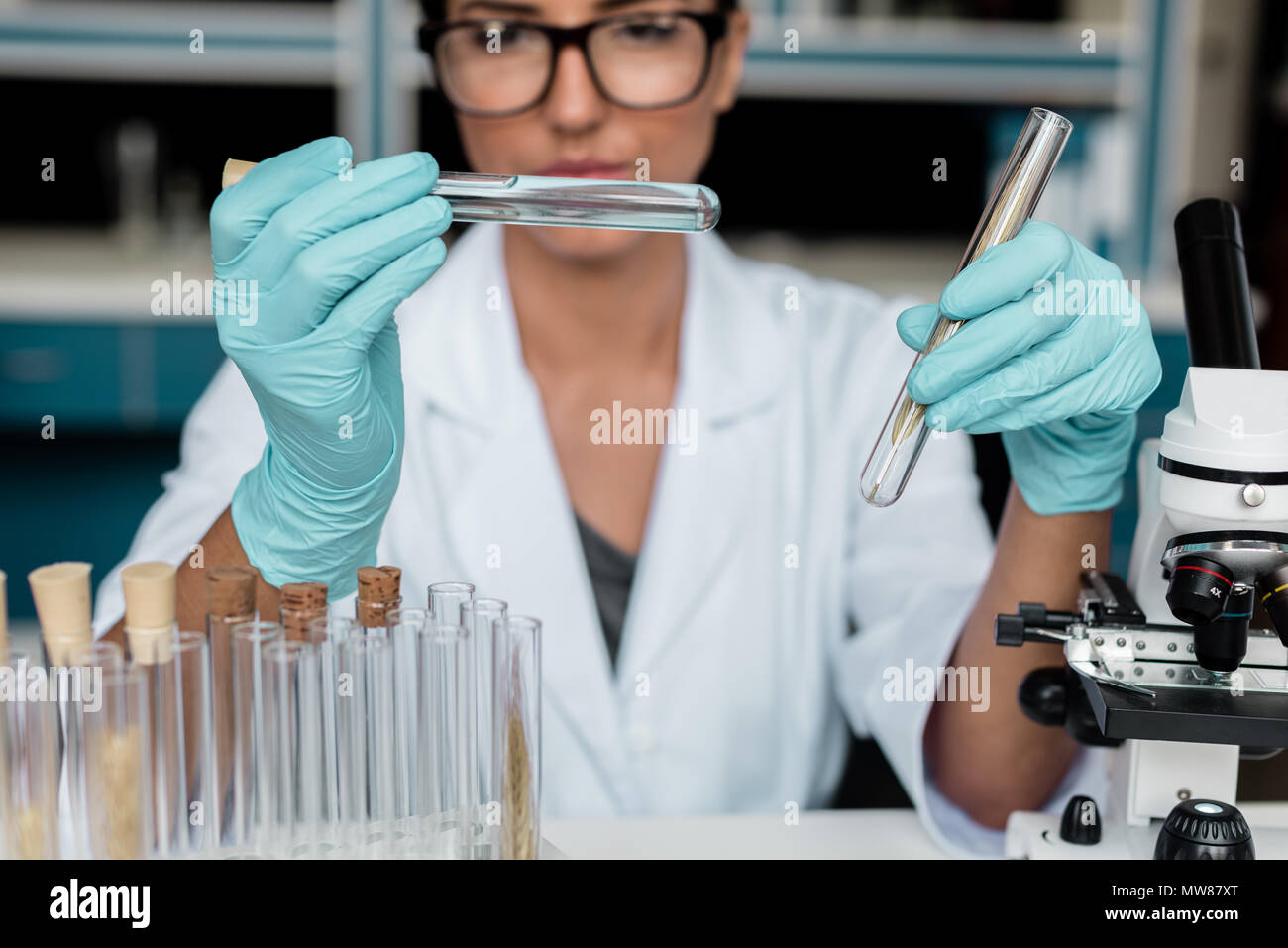 Professional scientist in white coat examining test tubes while making ...
