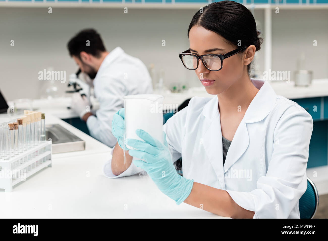 Concentrated young scientist in eyeglasses working in chemical ...