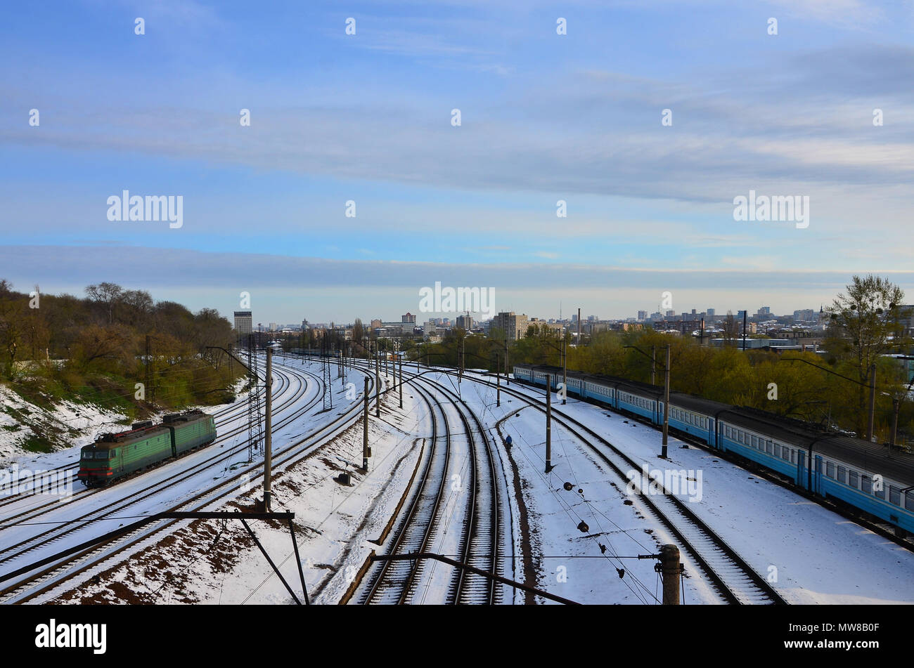 Winter landscape with a railway train on a railway surrounded by a city ...