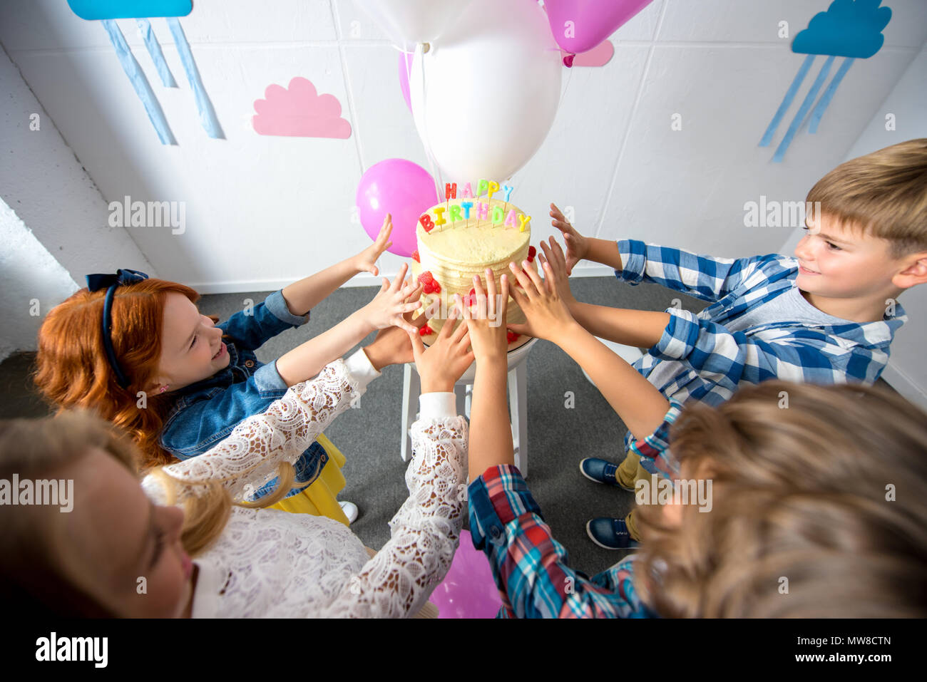 high angle view of cute little kids reaching to birthday cake Stock ...