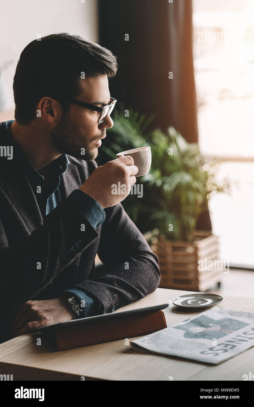 side view of young businessman drinking coffee while resting in coffee ...