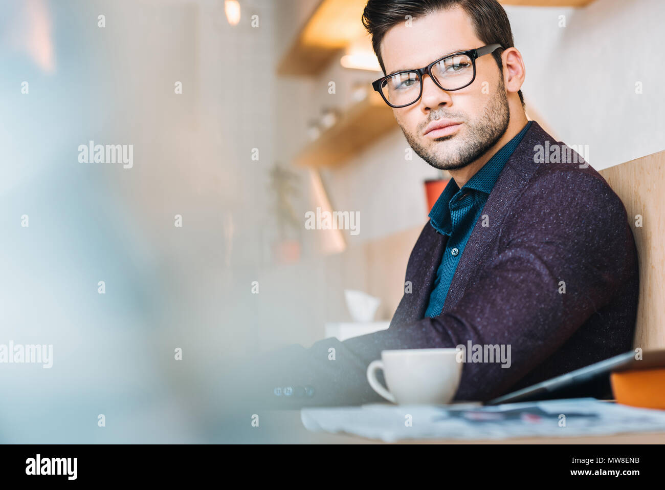 portrait of young businessman sitting at table with cup of coffee and ...