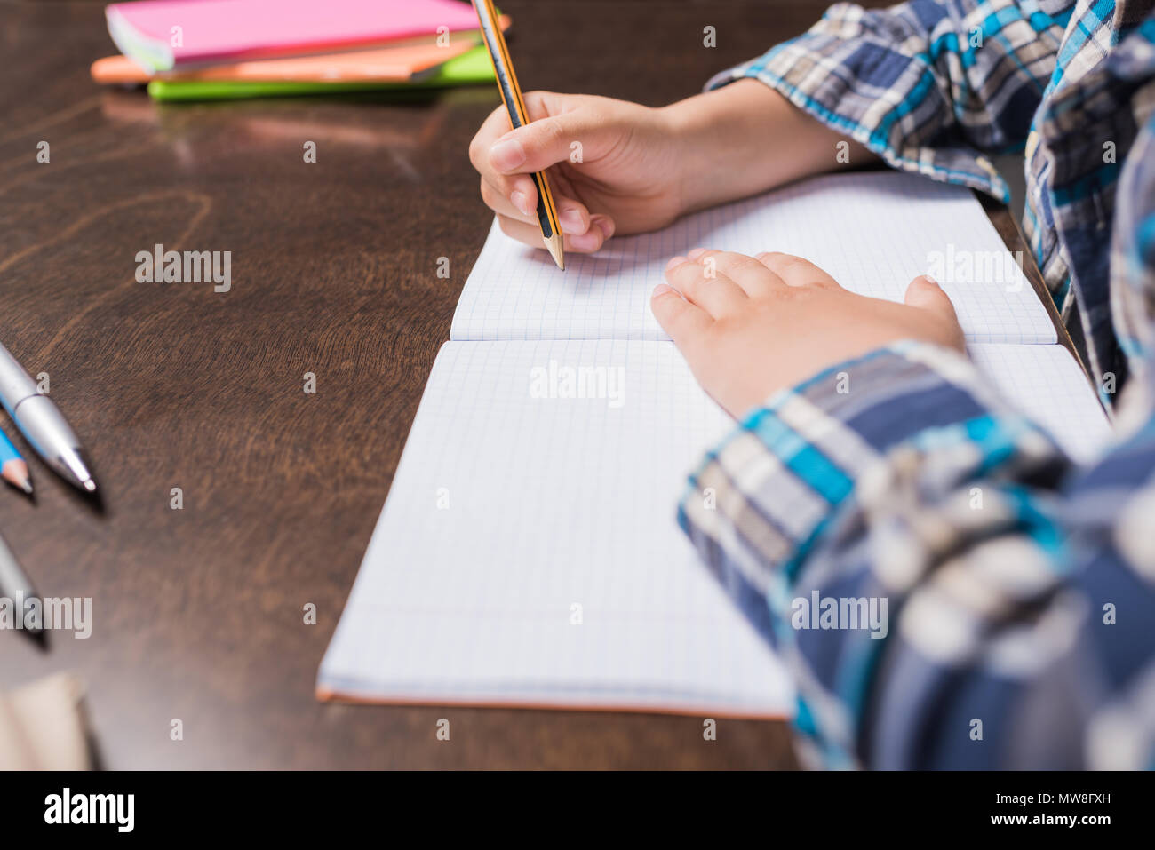 partial view of kid writing in notebook while doing homework Stock ...