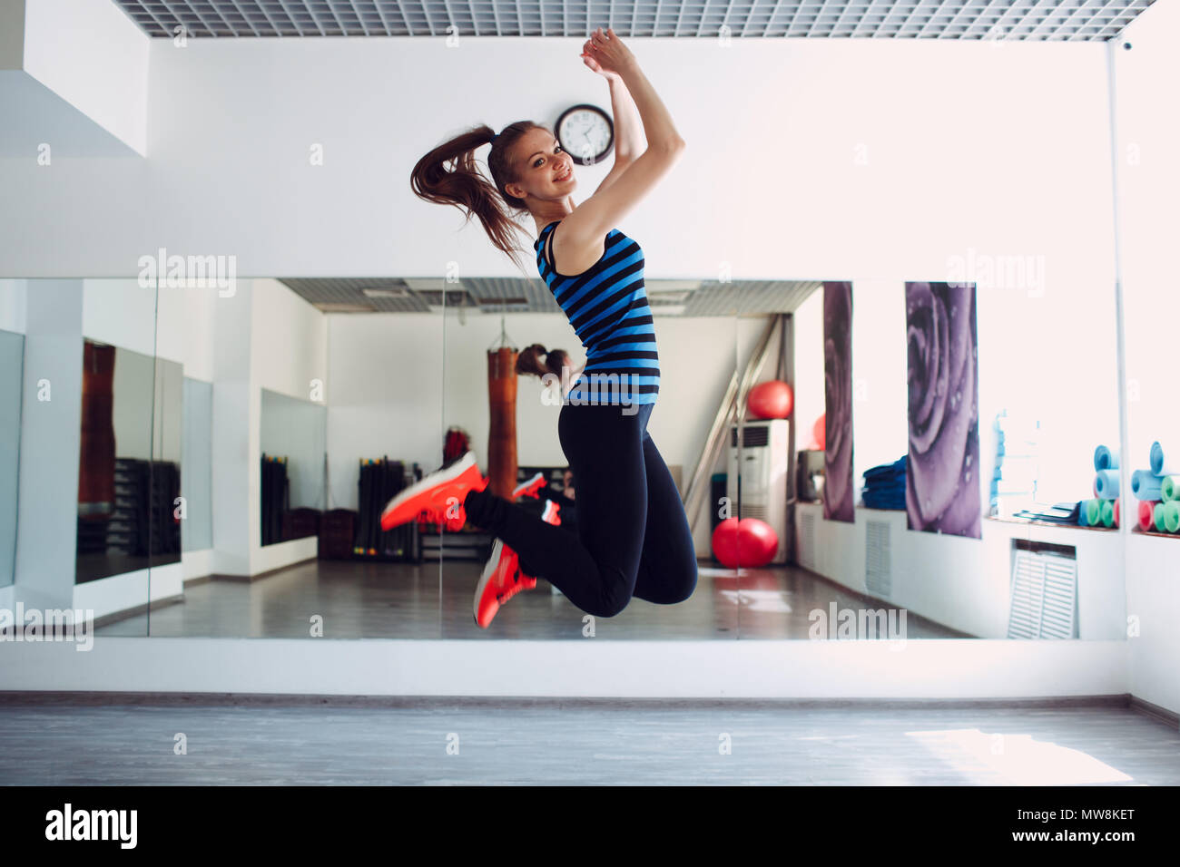 Young woman jumping in fitness gym Stock Photo - Alamy