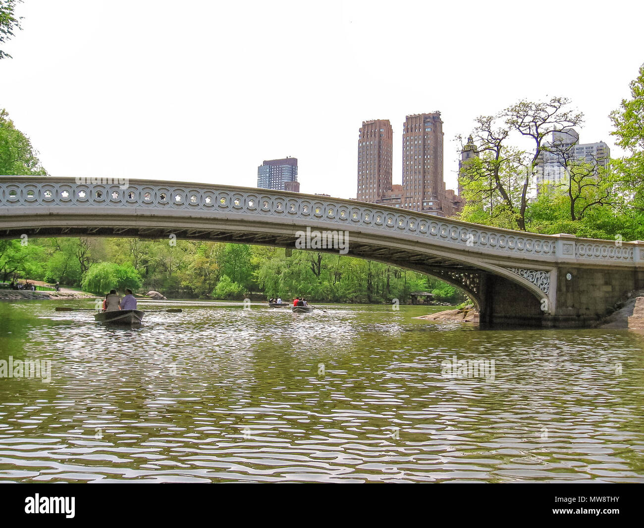 The famous Bow Bridge and tourists on canoe in the background in ...