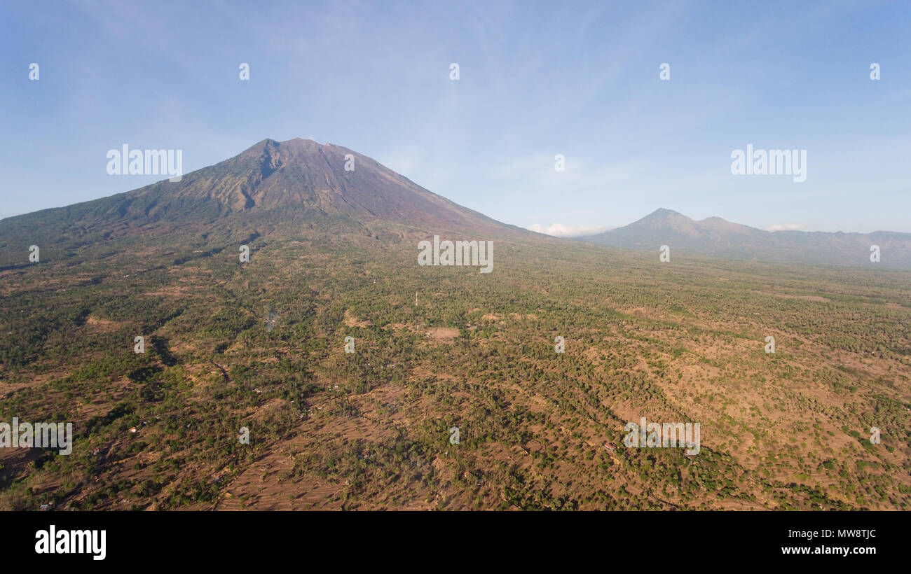 Aerial view of Volcano Mount Agung with smoke billowing out at sunrise ...