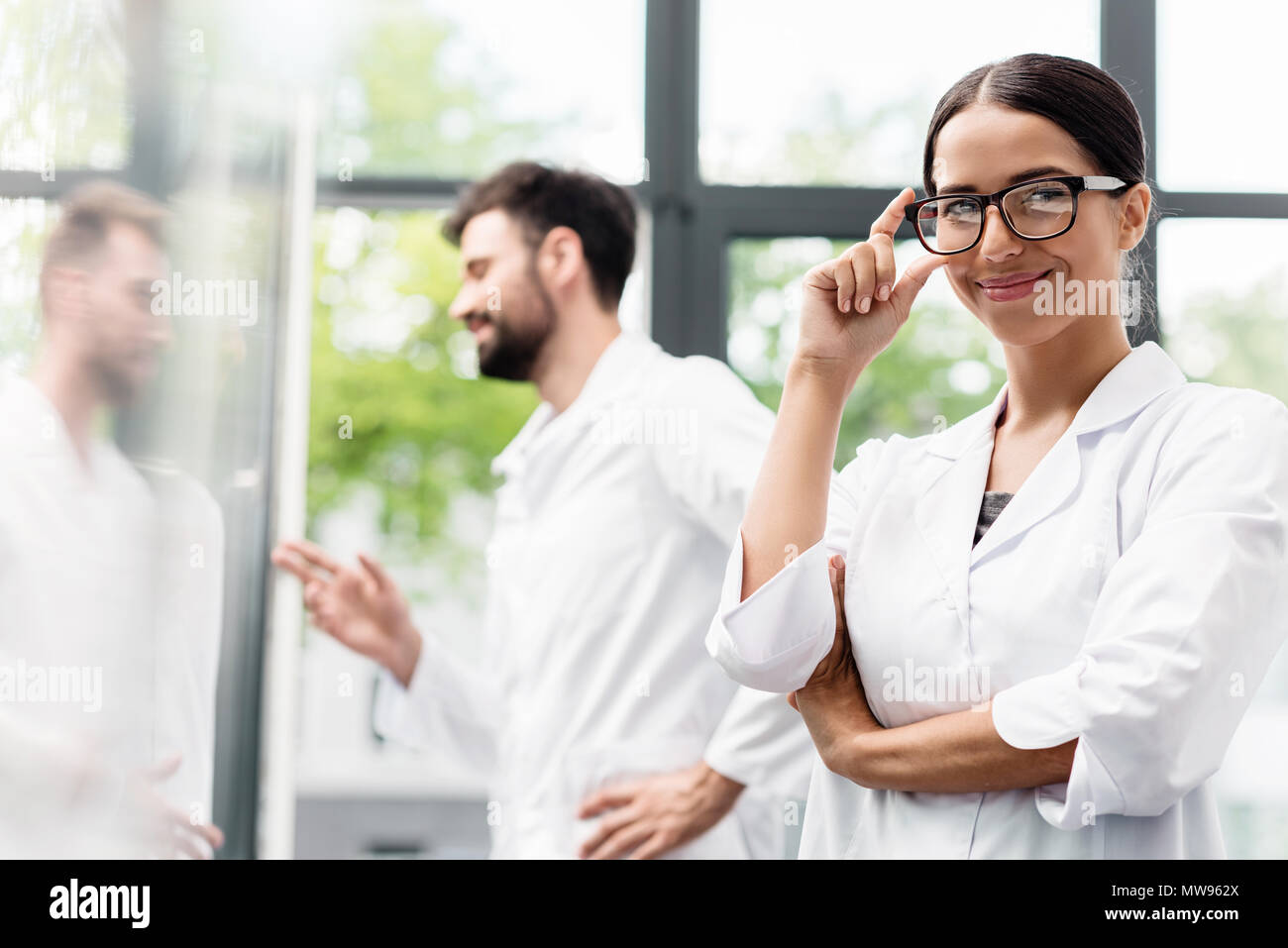 Team of professional scientists in white coats smiling while standing ...