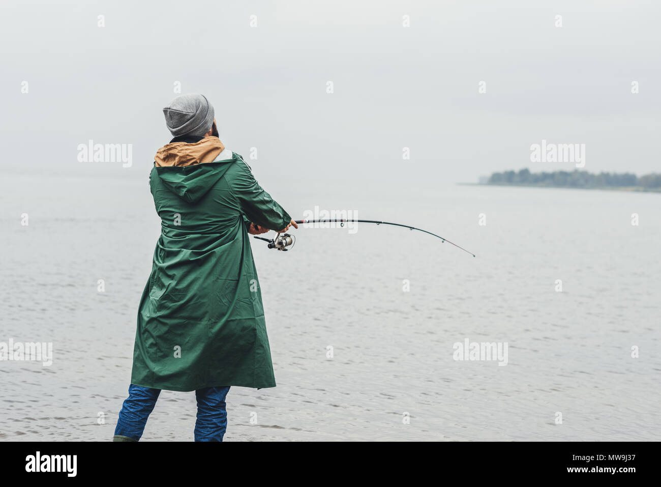 lonely man pulling rod while fishing on rainy autumn day Stock Photo ...