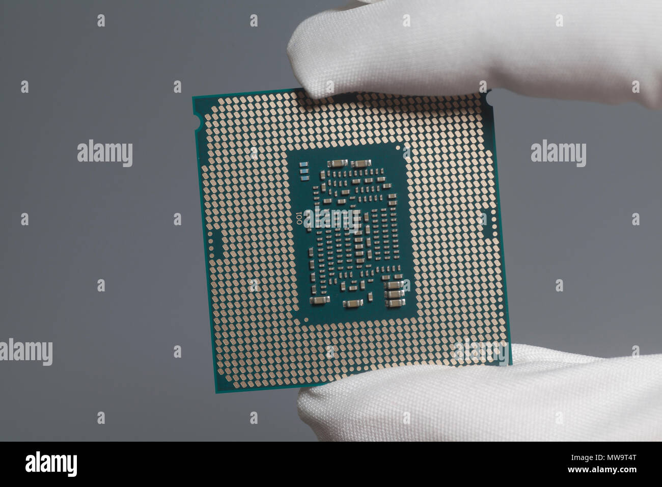 Hand in white glove holding a CPU computer processor microchip on gray ...