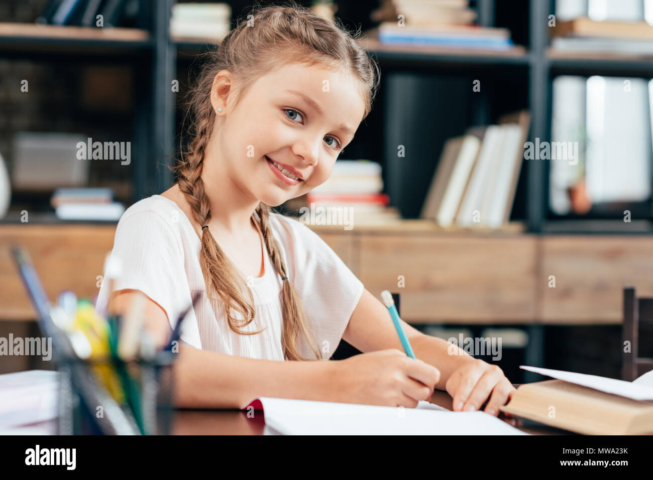 happy smiling little girl writing homework Stock Photo - Alamy