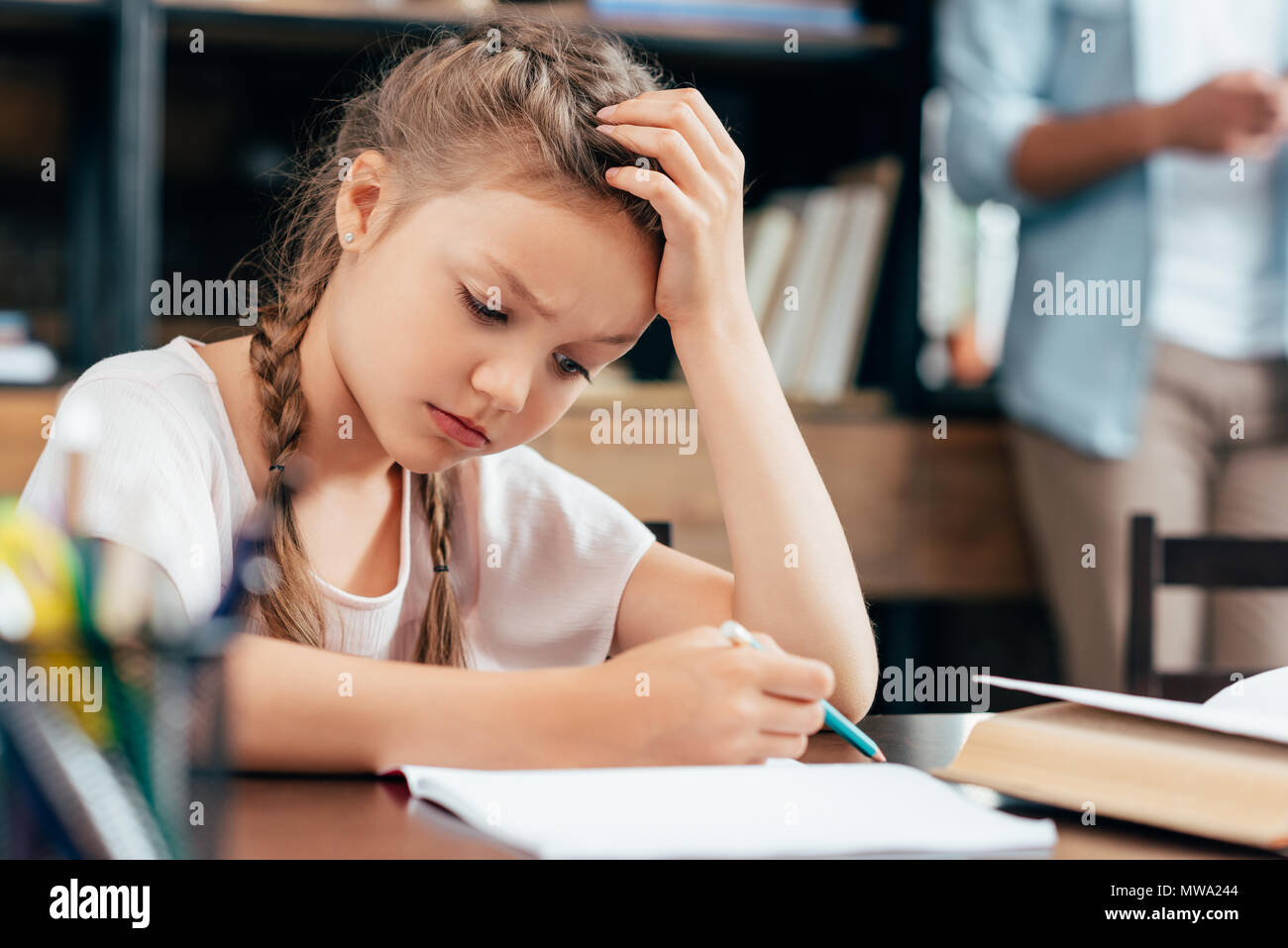 depressed little girl writing homework Stock Photo - Alamy