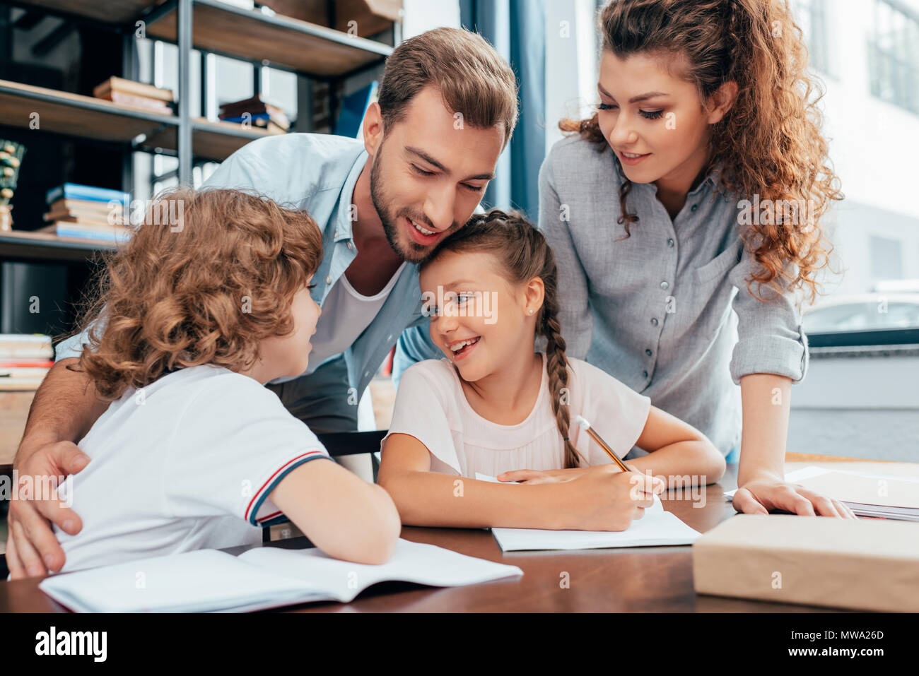 beautiful young parents doing homework with kids Stock Photo - Alamy